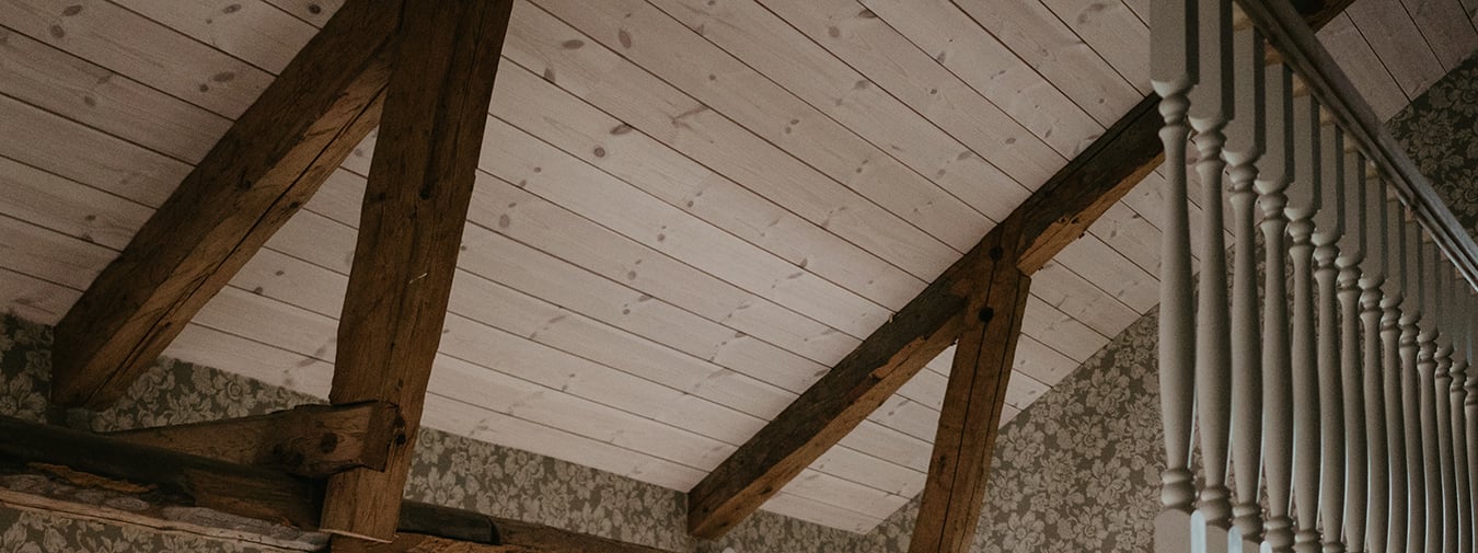 Vitvaxad panel och synliga takbjälkar i snedtak - Johanna berättar!